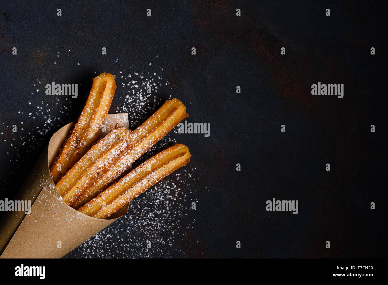 Churros sticks fresh hot in paper bag on dark background with copy ...