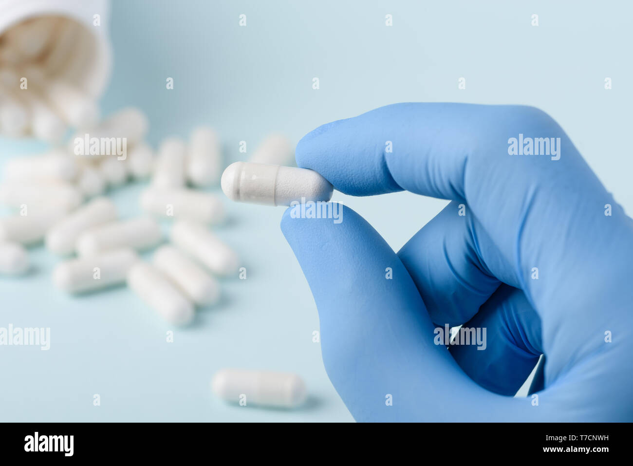 Single pill in scientist hand with bottle on background Stock Photo - Alamy