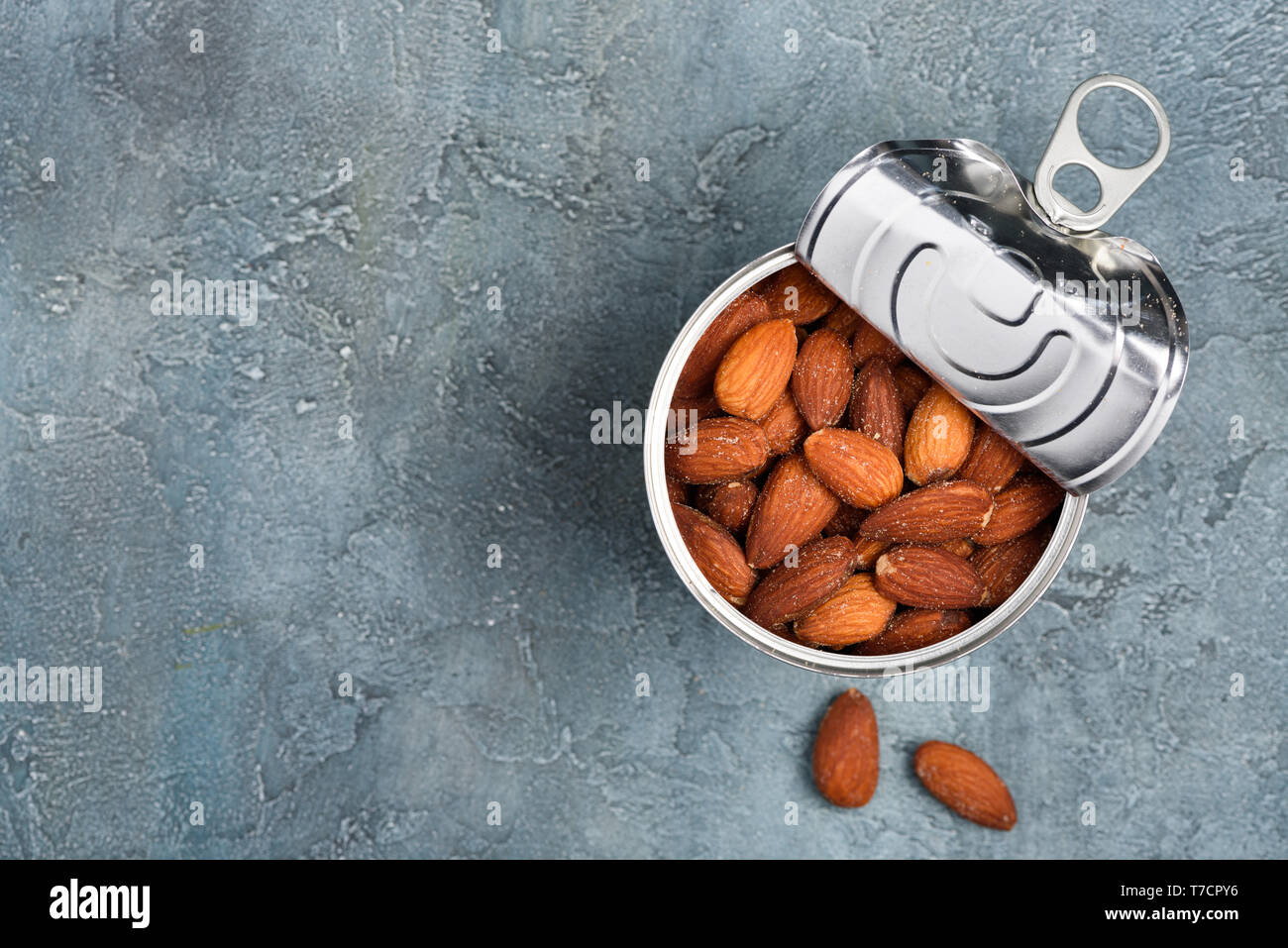 Almonds nuts roasted and salted in open tin can on rustic table with ...