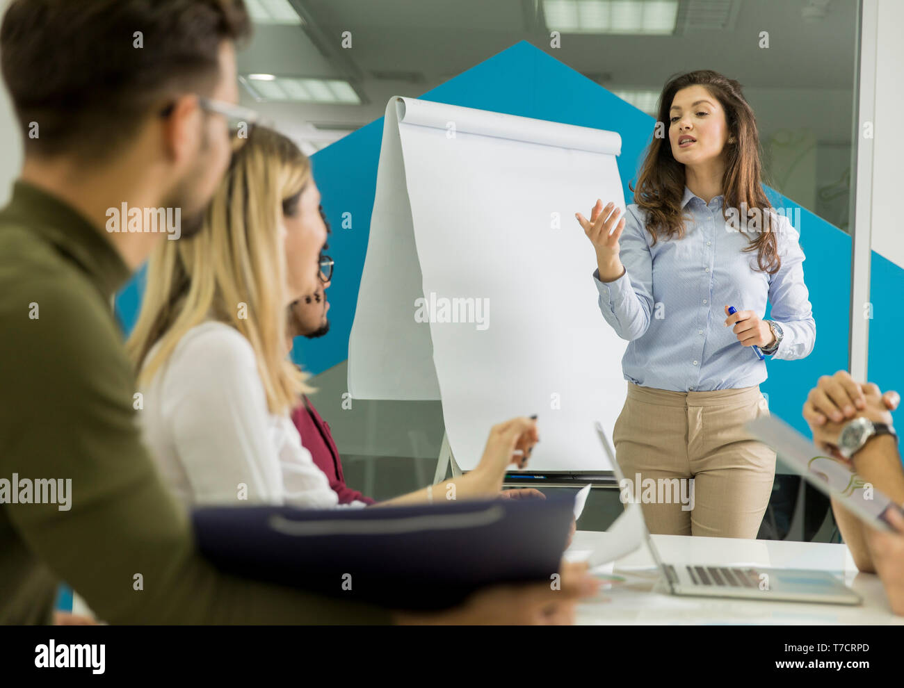 Confident young team leader giving a presentation to a group of young ...