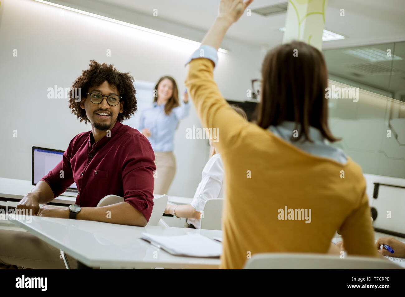 Group of young students rising hands to answer the question during the ...