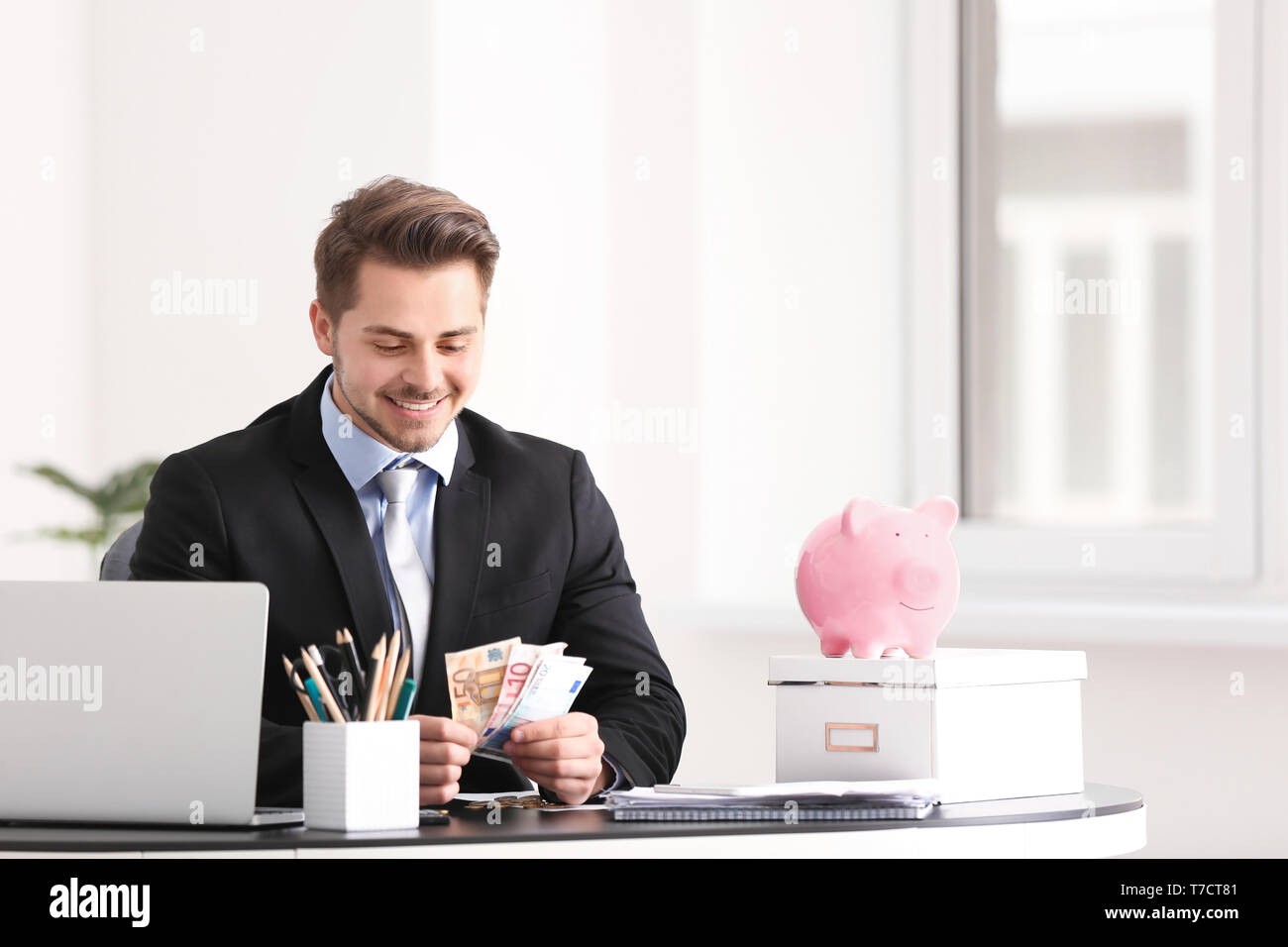 Young businessman counting money at table indoors. Money savings ...