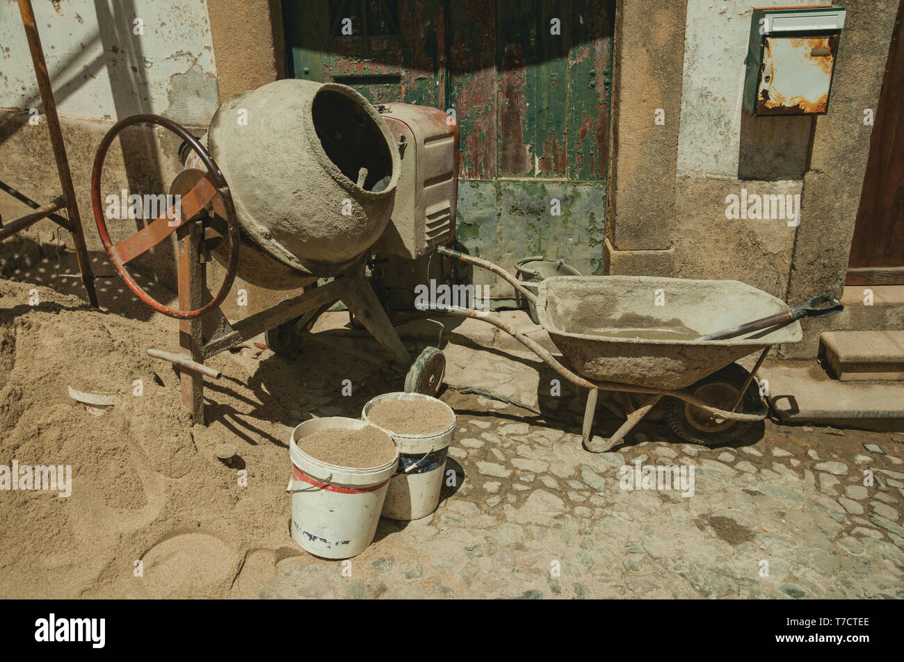 Old cement mixer with pushcart and sand buckets in a construction at ...