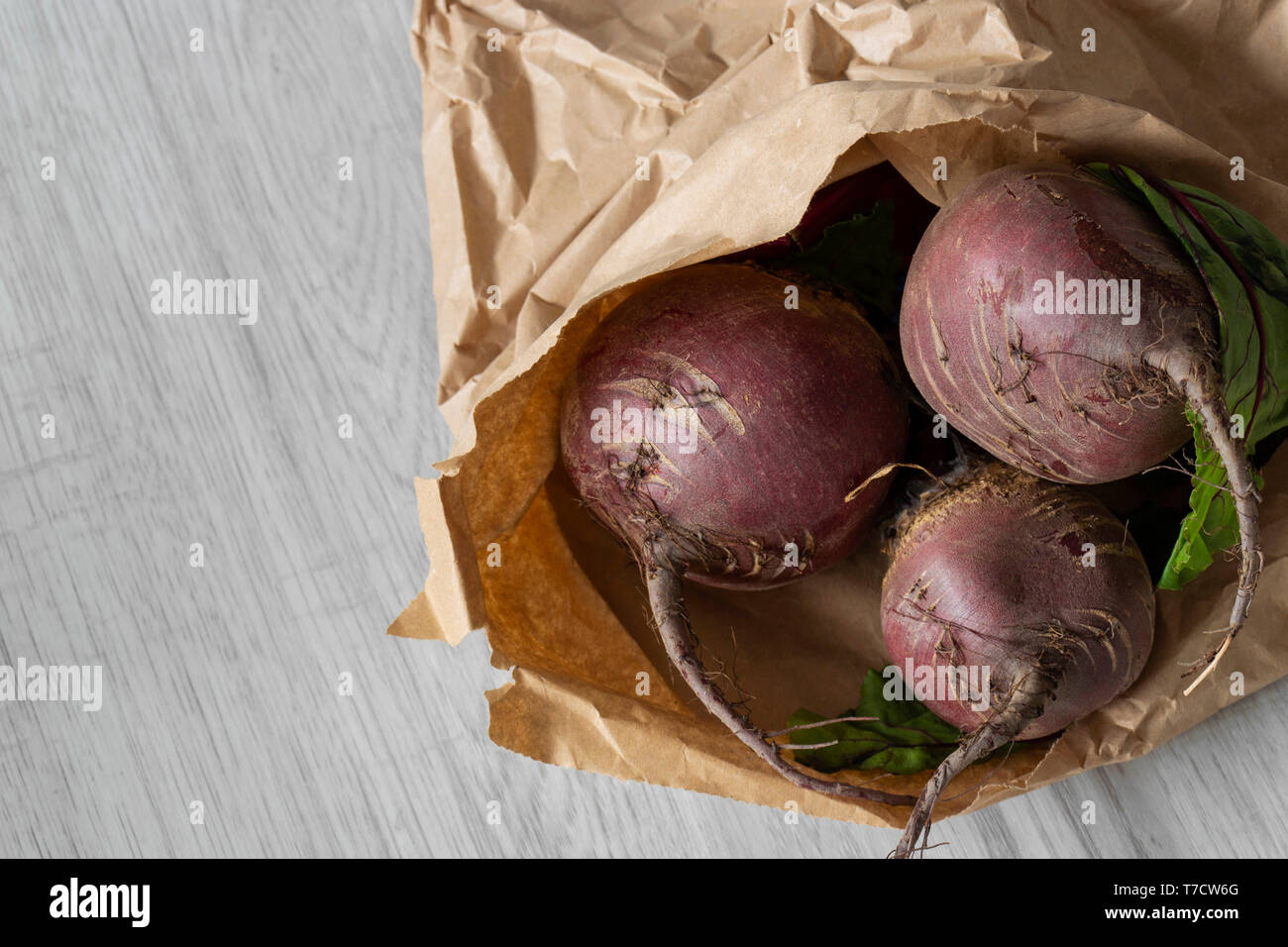 Organic beetroot in a brown paper bag on grey wood. Recycle packaging ...