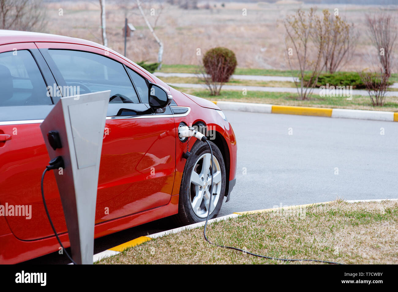 EV Car or Electric red car at charging station with the power cable ...