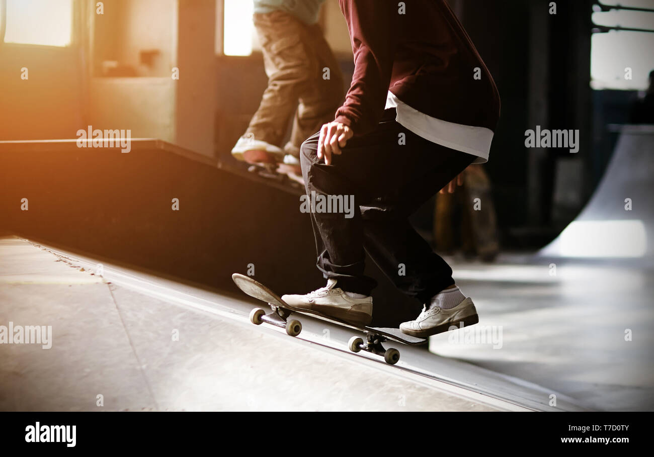 A fashionably dressed guy rides a skateboard on a ramp illuminated by ...