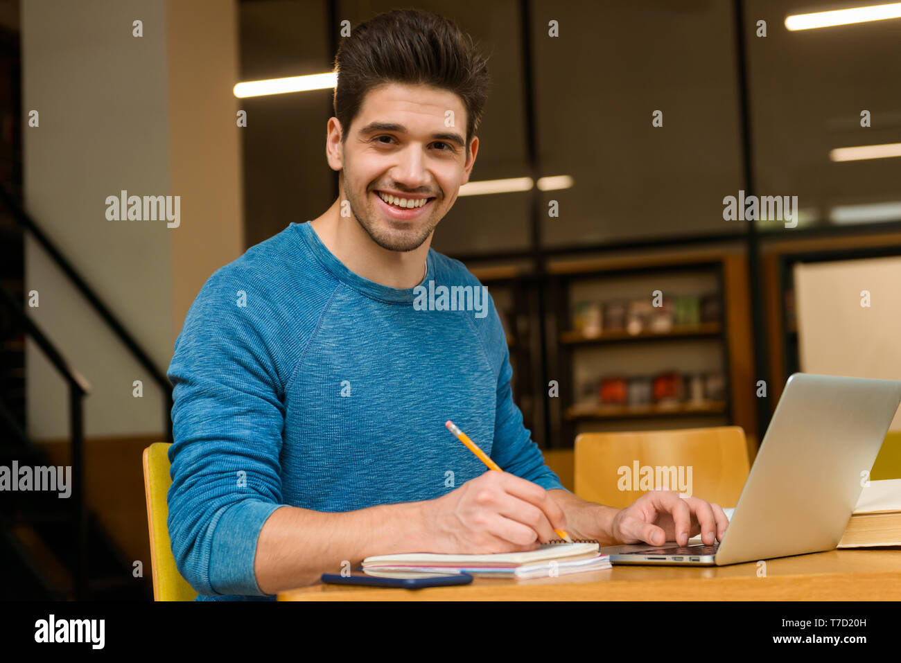 Image of a young student happy man in library doing homework studying ...