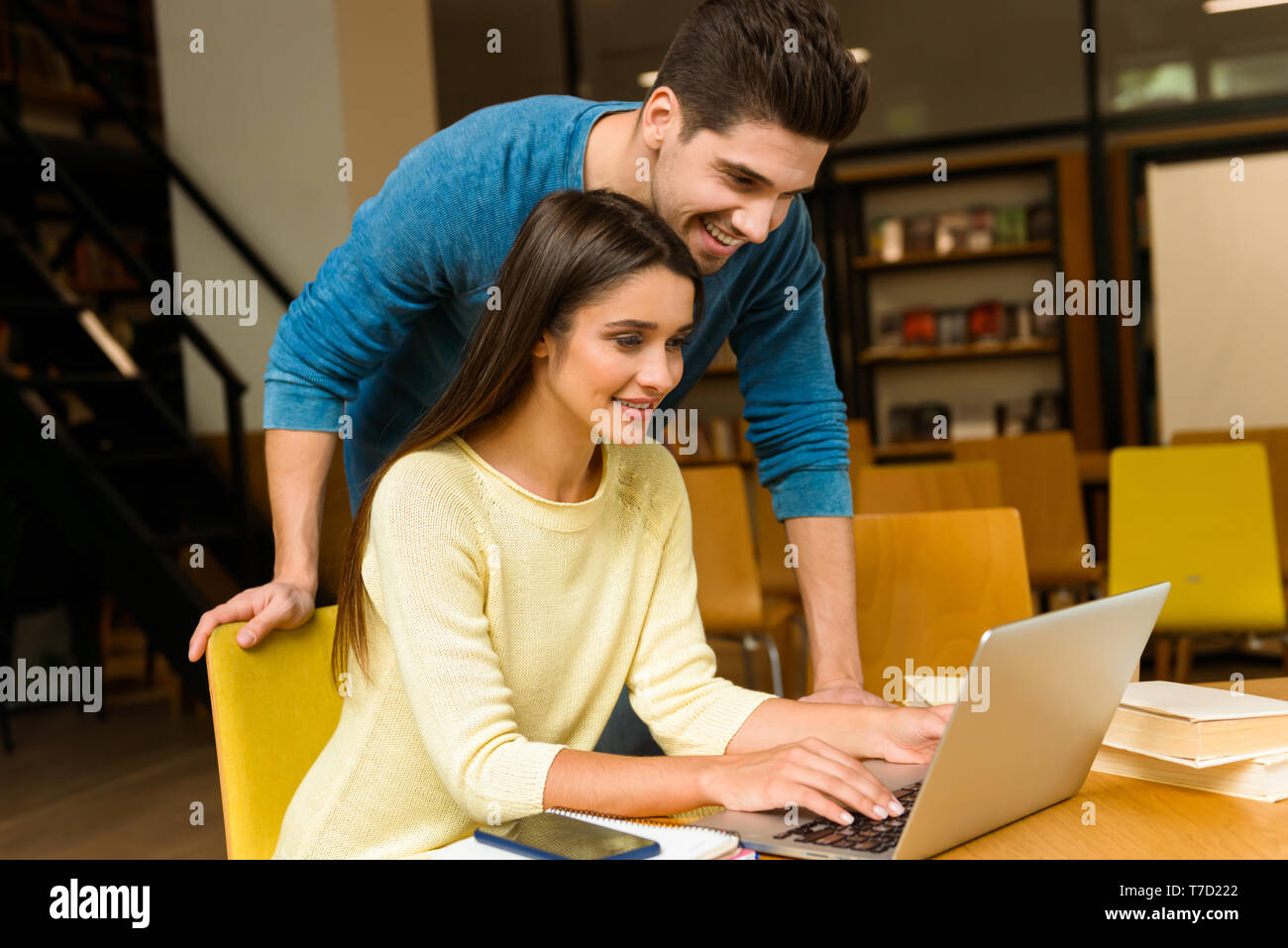 Photo of a two young students friends couple in library doing homework ...