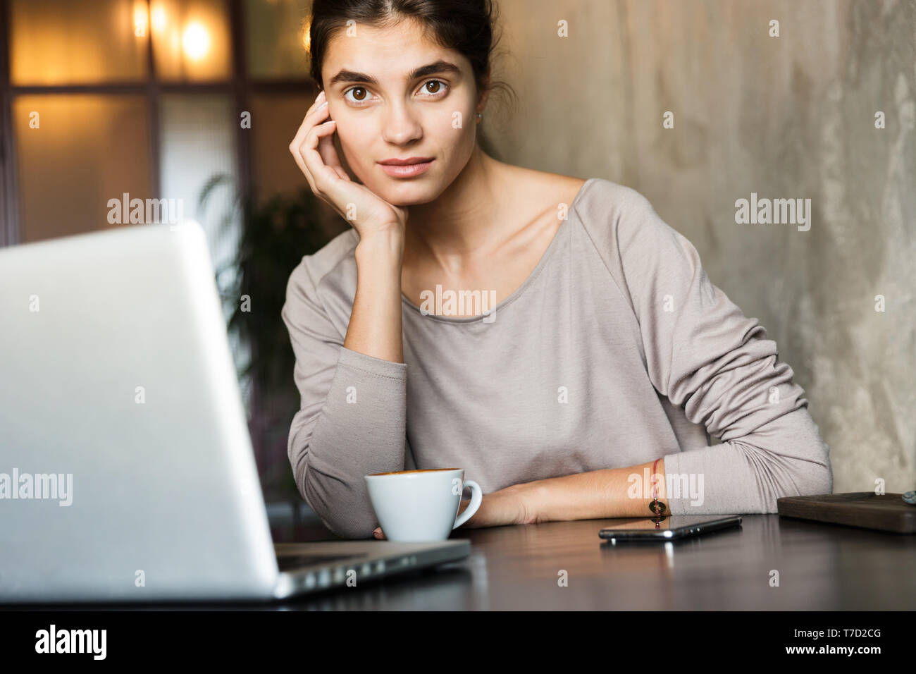 Image of pretty young woman sitting in cafe drinking coffee indoors ...