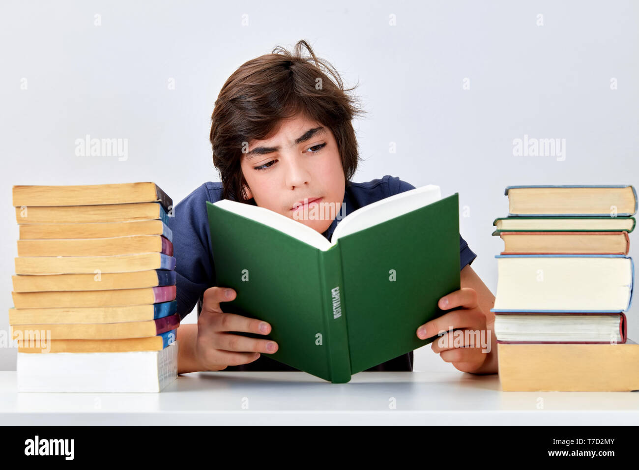Teenage kid with serious concentrated expression sitting at the desk ...