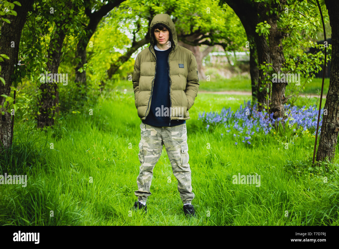 Model standing under archway created by trees wearing camo pants Stock ...