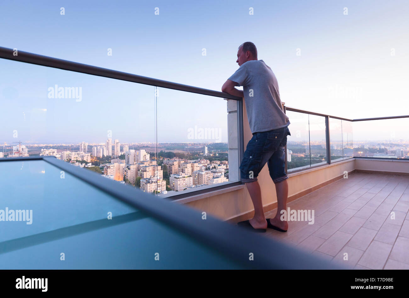 High end balcony in downtown of modern city. Man on the balcony look on ...