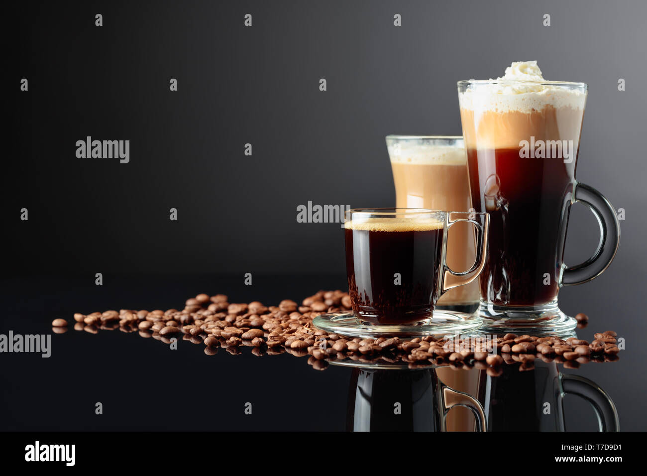 Various coffee drinks and coffee beans on black reflective background ...