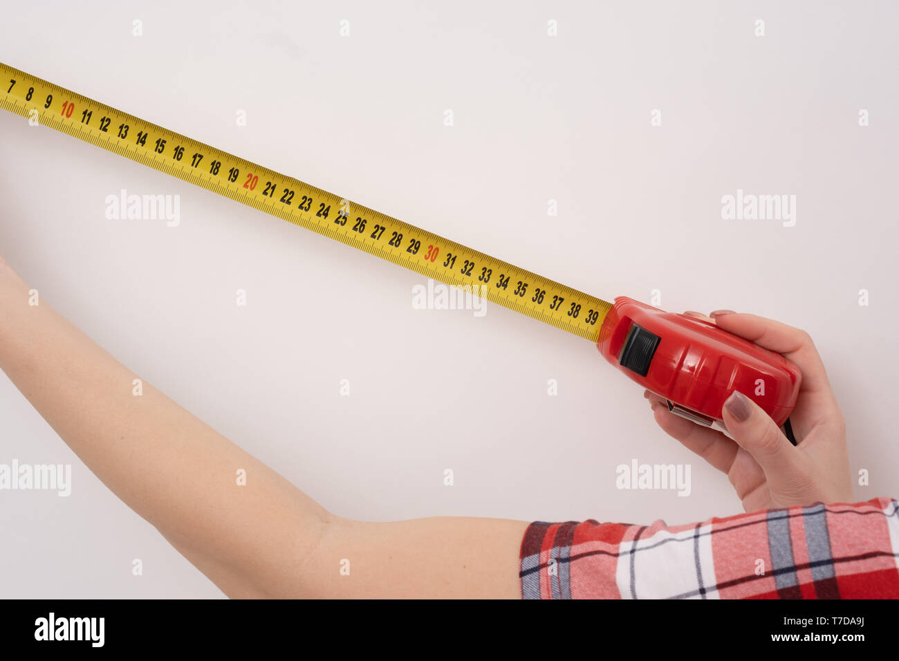 A female hands hold a yellow tape centimeter measure on white, top view ...