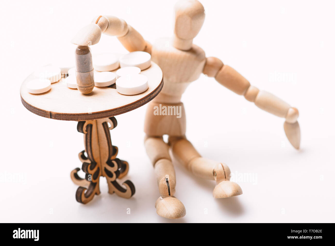 Pills on tiny wooden table. Medication regimen. Human wooden dummy near ...