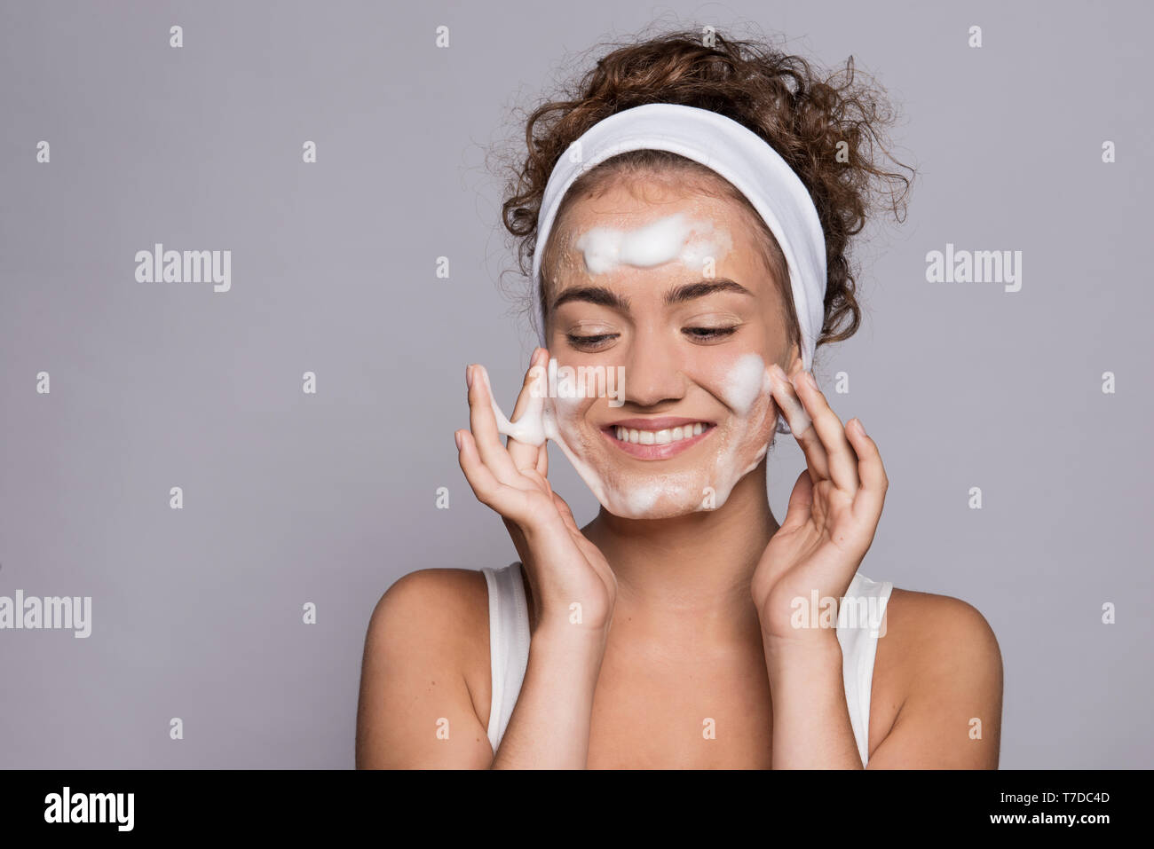 A portrait of a young woman cleaning face in a studio, beauty and skin ...