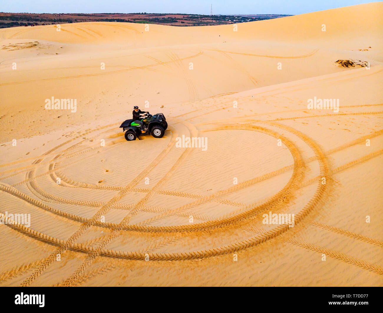 A tourist men on a Quad bike rides around on a sand dune in the desert ...