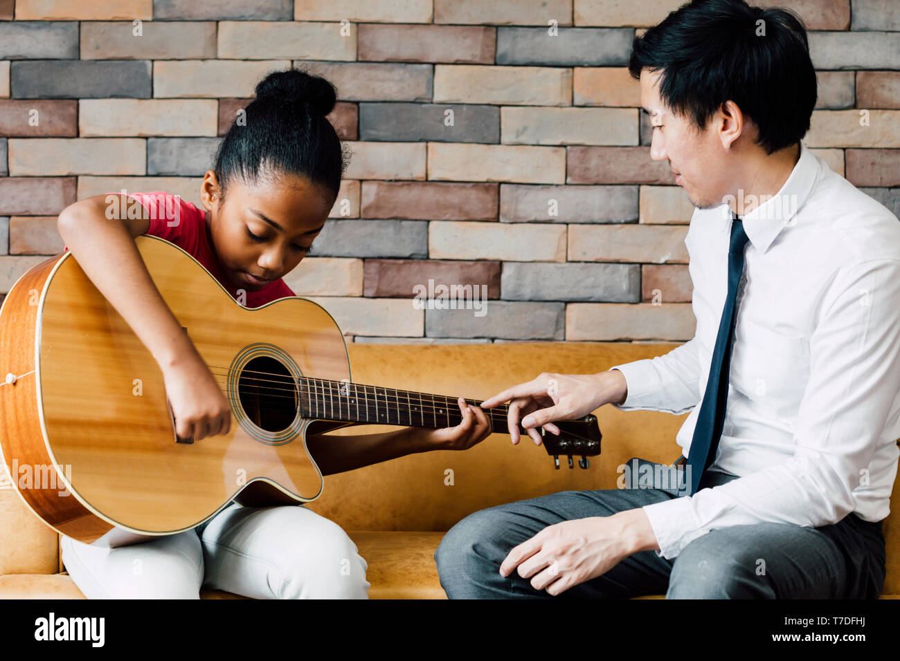Young Asian male teacher giving a guitar lesson and teaching how to ...
