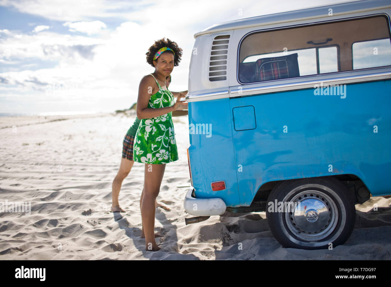 Young woman and young man pushing van stuck in the sand Stock Photo - Alamy