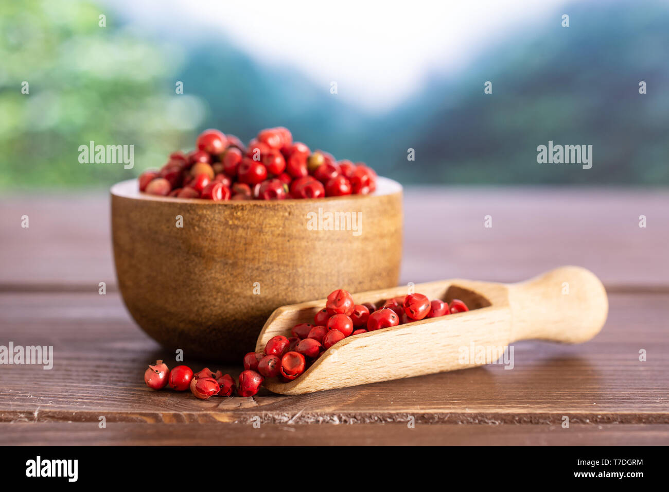 Lot of whole peruvian pink pepper in a wooden bowl with wooden scoop in ...