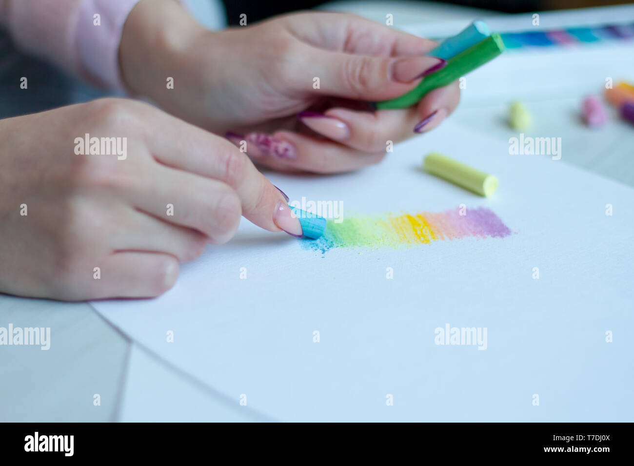 Close-up of female hands are drawing with multicolored chalks on a ...