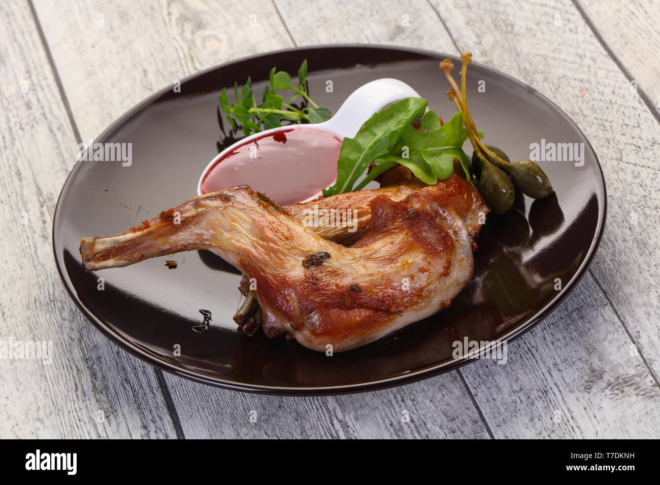 Roasted rabbit legs with cowberry sauce Stock Photo - Alamy