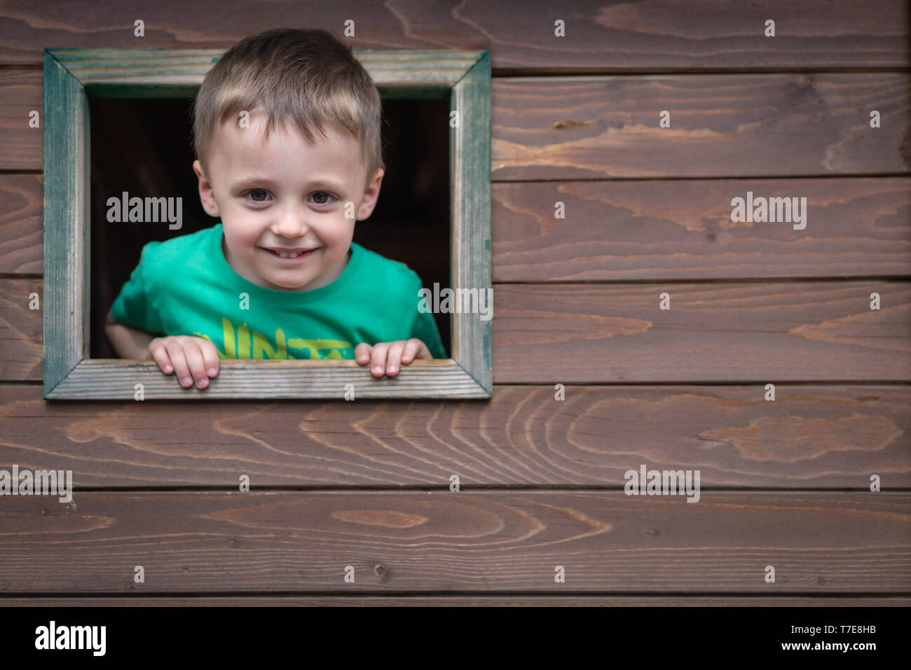 Portrait of a cute little Caucasian boy looking through the window of a ...