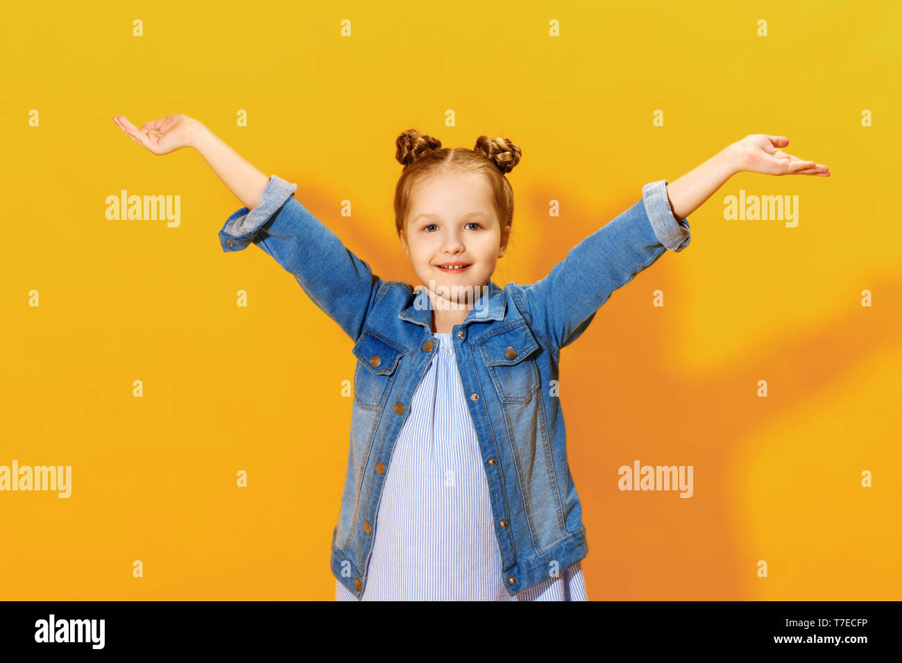 Closeup portrait of a charming little kid girl on a yellow background ...