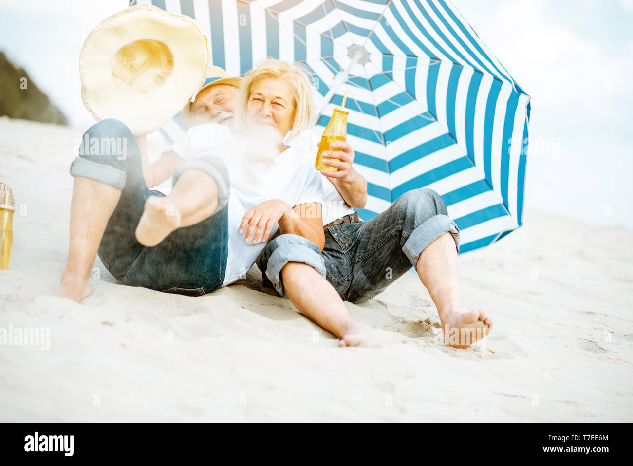 Happy senior couple having fun, playing with sand on the beach ...