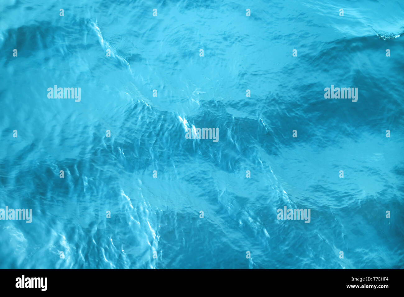 Closeup of calm river water surface with water splashes in blue color ...