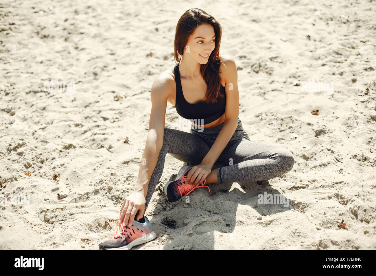 Sports girl. Woman sitting on a sand. Lady in a sports wear Stock Photo ...