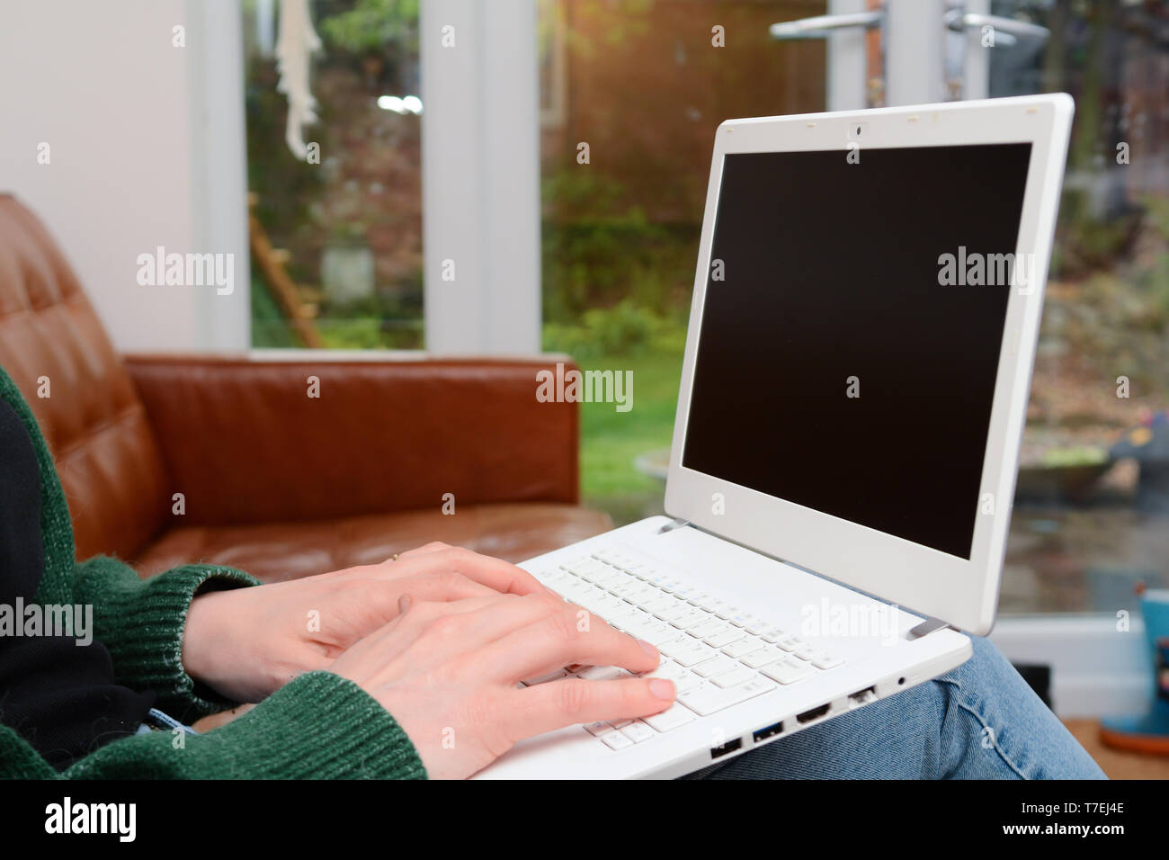 Woman at home using laptop computer whilst relaxing on the couch Stock ...