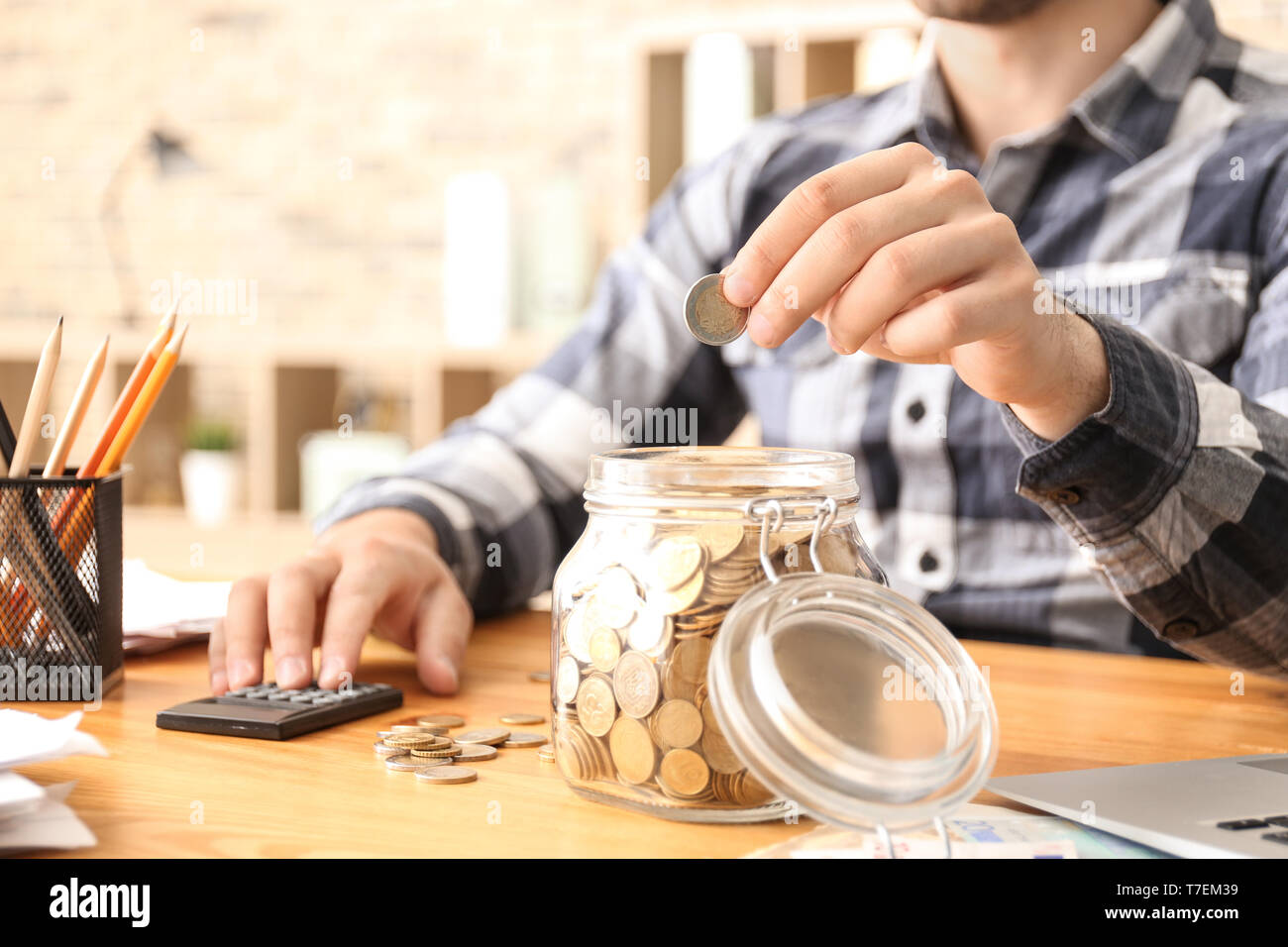 Man putting coin into glass jar indoors. Money savings concept Stock ...