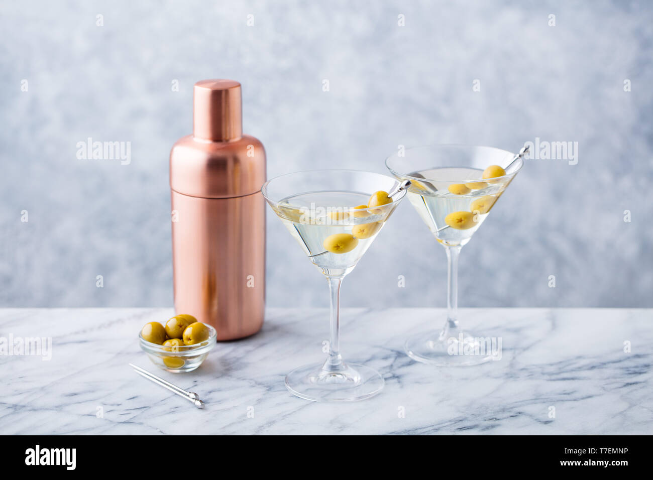 Martini cocktail with green olives, shaker on marble table background ...