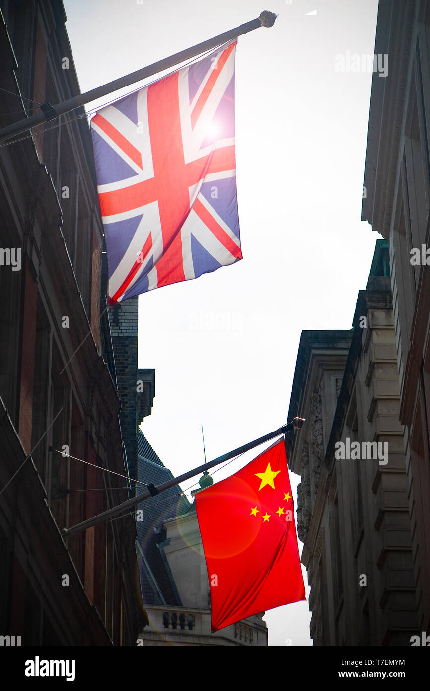 Sun shines through the flags of Great Britain and China in the City of ...