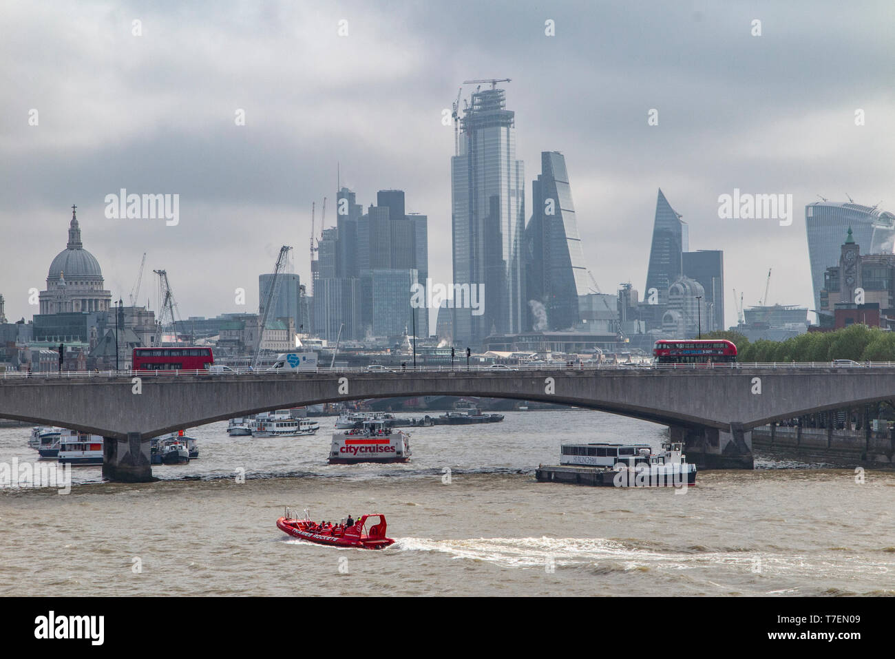 Busy waterway with lots of boats on the River Thames with the City of ...