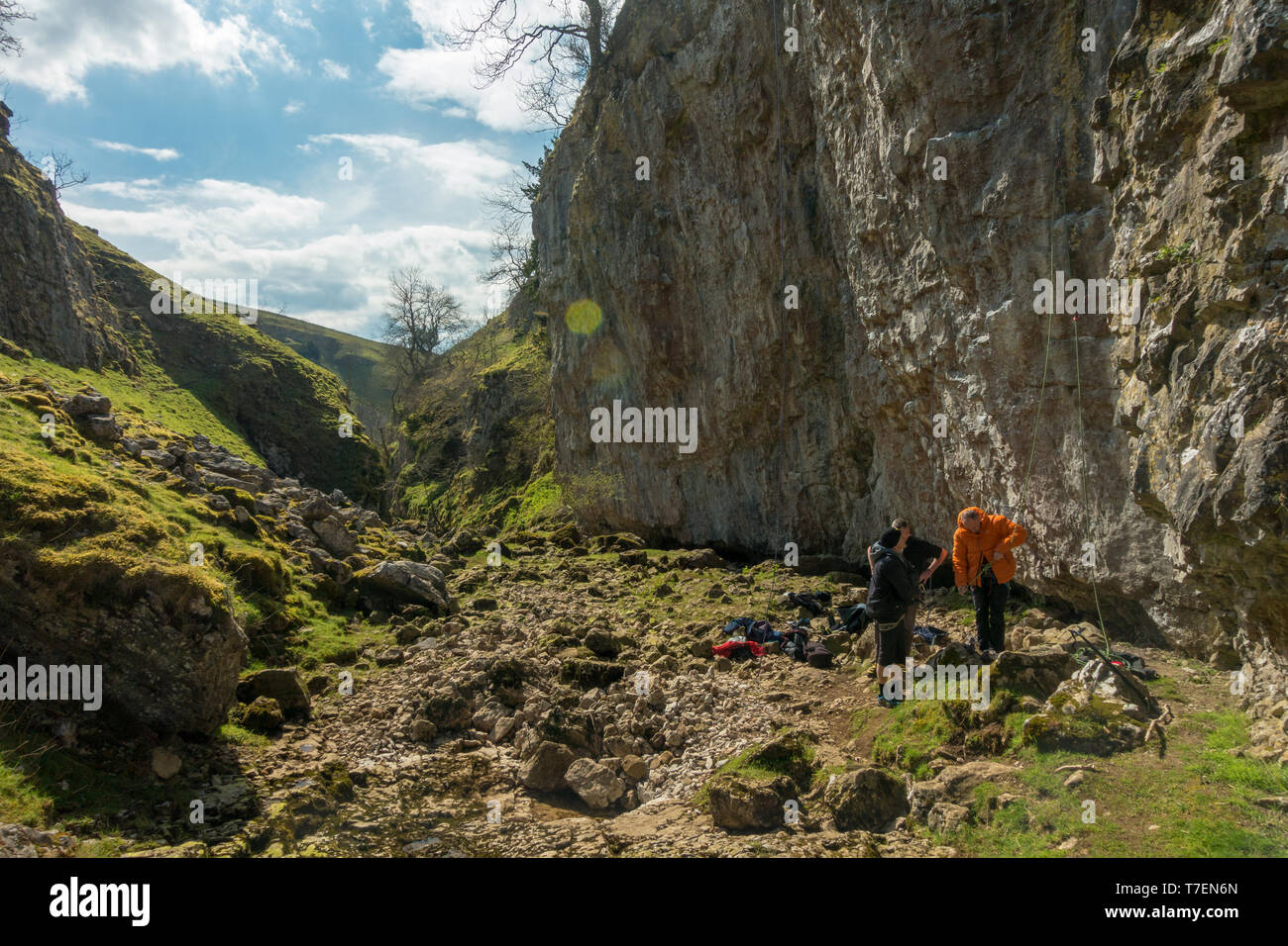 Men socialising: Rock climbers tying in to a rope on a route in Troller ...