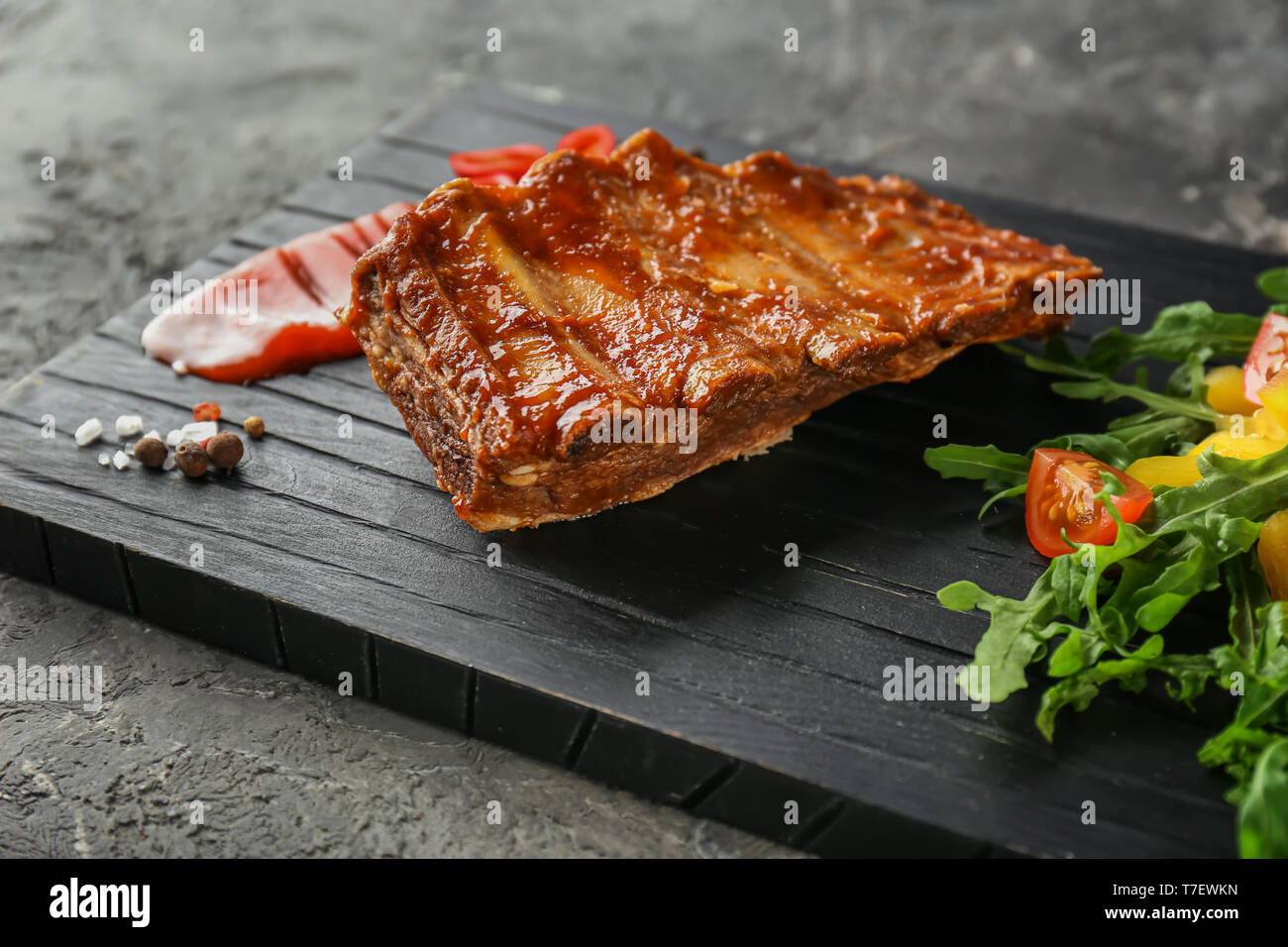 Wooden board with delicious grilled ribs and vegetable salad Stock ...