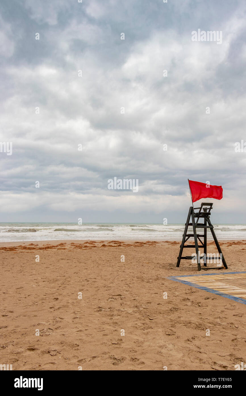 Red danger flag flying before a storm, on a windy and cloudy day on a ...
