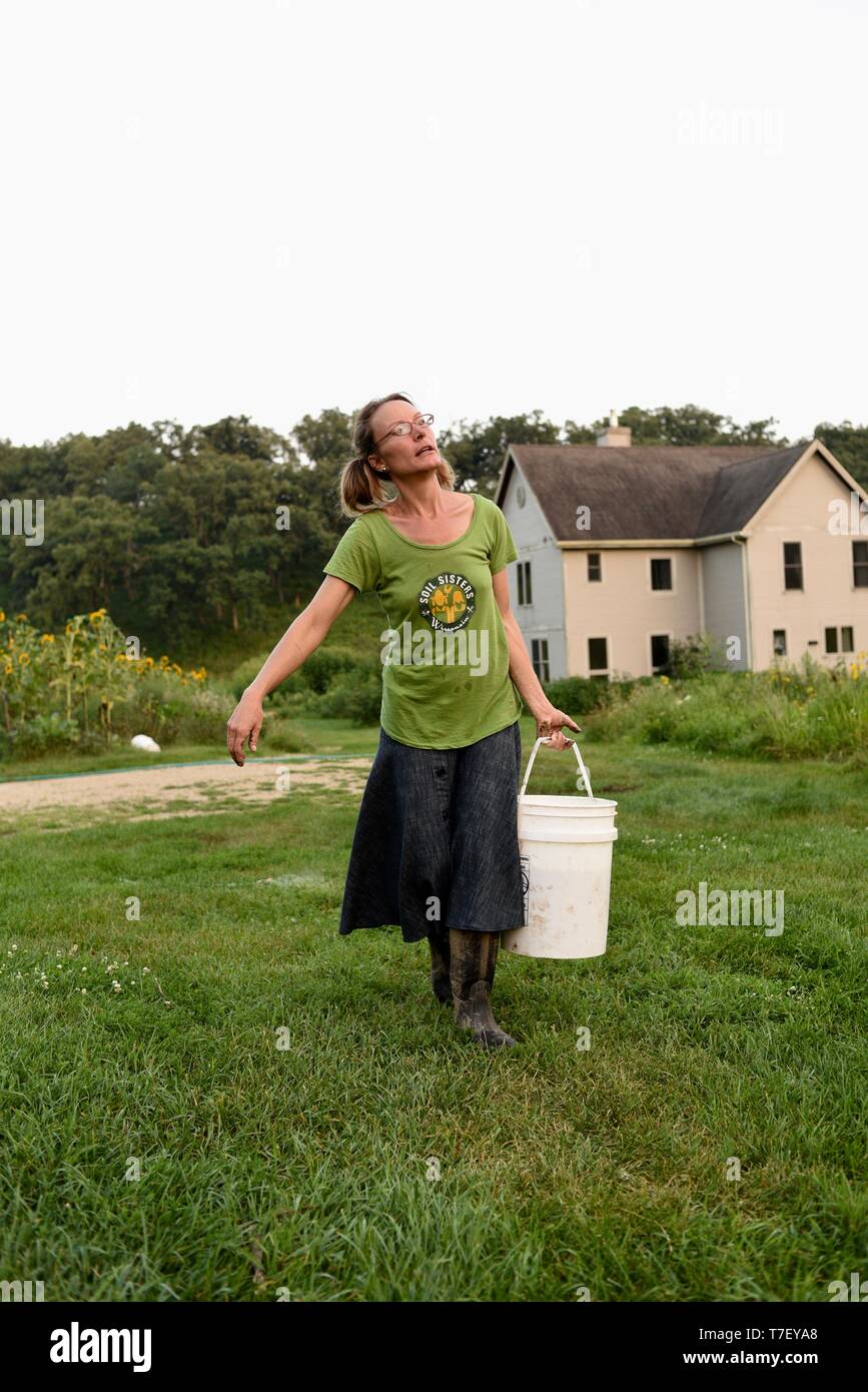 Woman farmer on her working pig farm, feeding heritage hog breed with ...