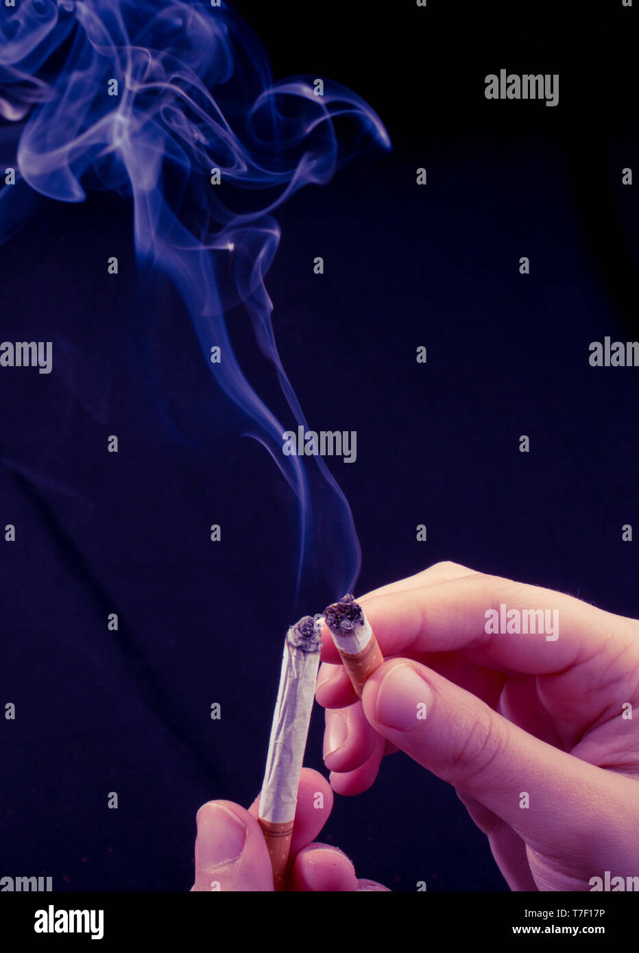 Hand is holding smoking cigarette with smoke around Stock Photo - Alamy