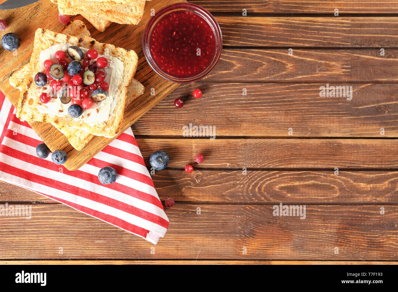 Tasty sweet toasts with jam and fresh berries on wooden table Stock ...