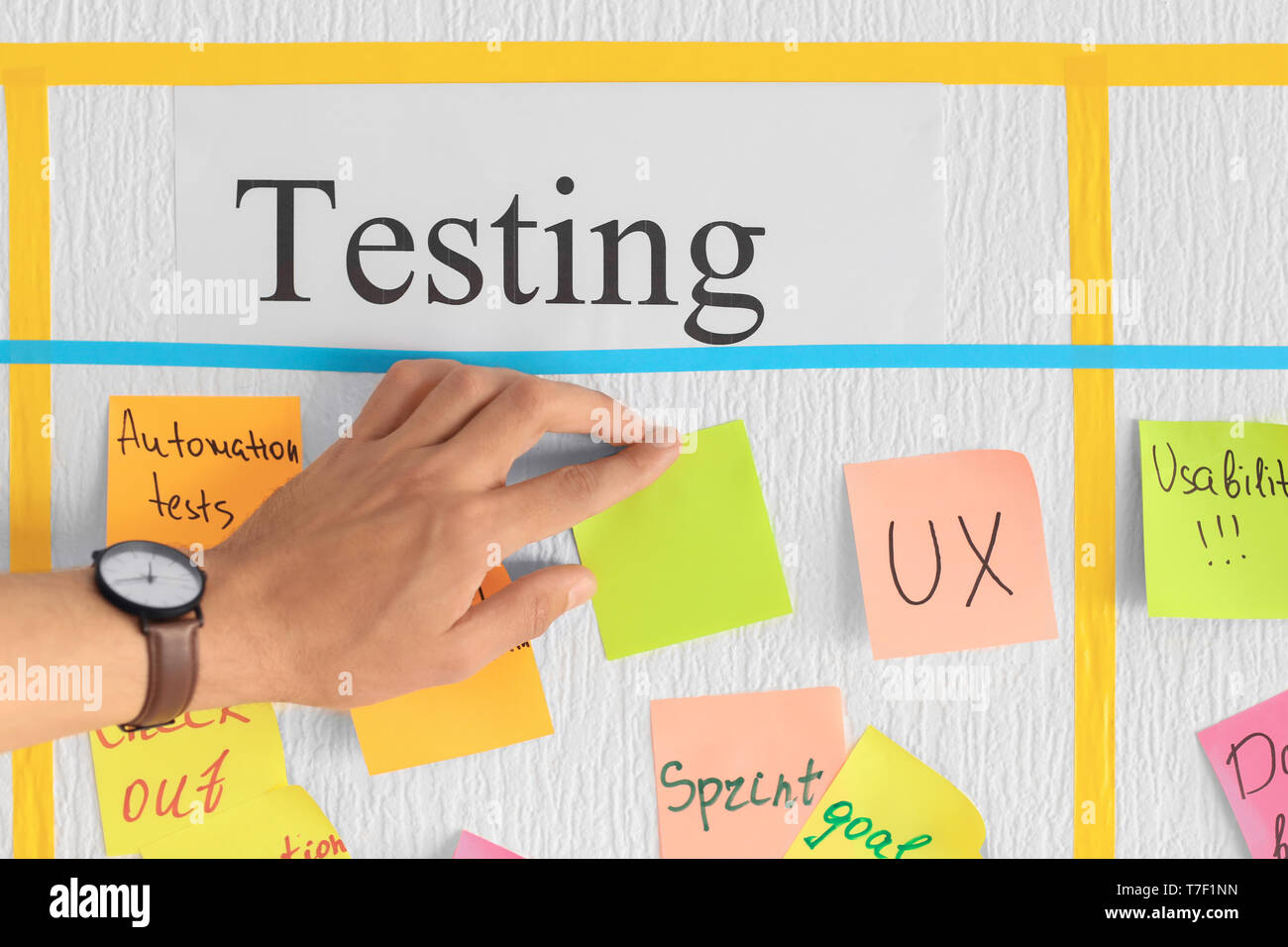 Man attaching sticky note to scrum task board in office Stock Photo - Alamy