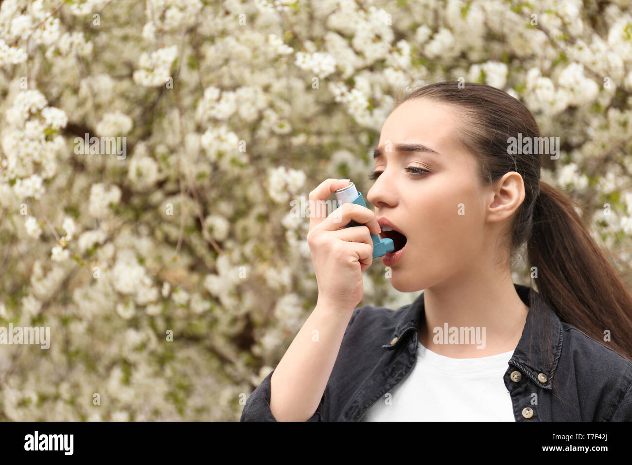 Young woman using inhaler near blooming tree. Allergy concept Stock ...