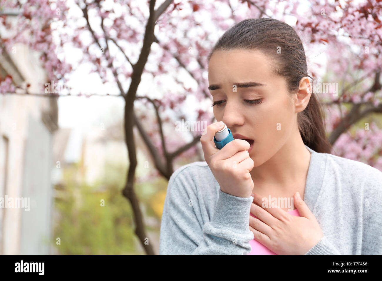 Young woman using inhaler near blooming tree. Allergy concept Stock ...