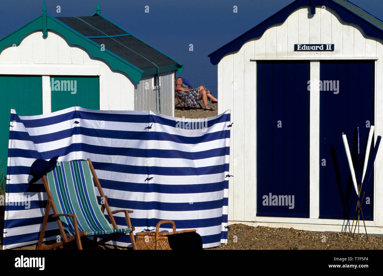Deck chair in front of striped wind break beside beach hut Stock Photo ...