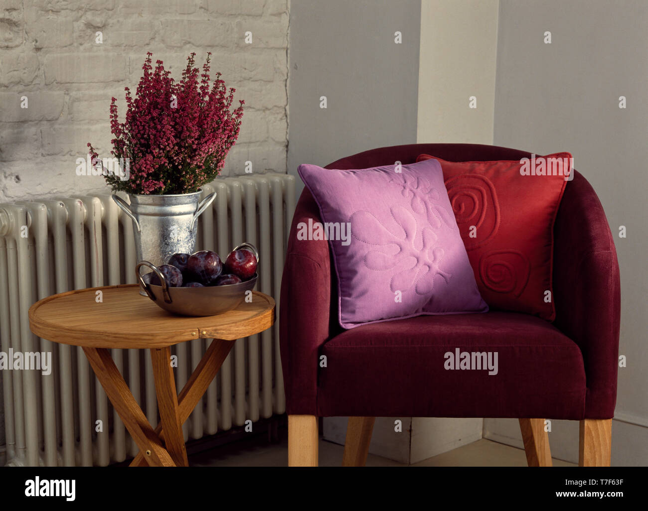 Small rustic table beside red tub chair Stock Photo - Alamy