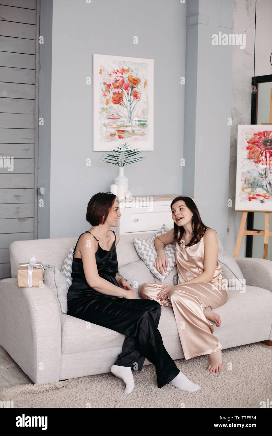 Two young sisters sitting on sofa at home and talking Stock Photo - Alamy