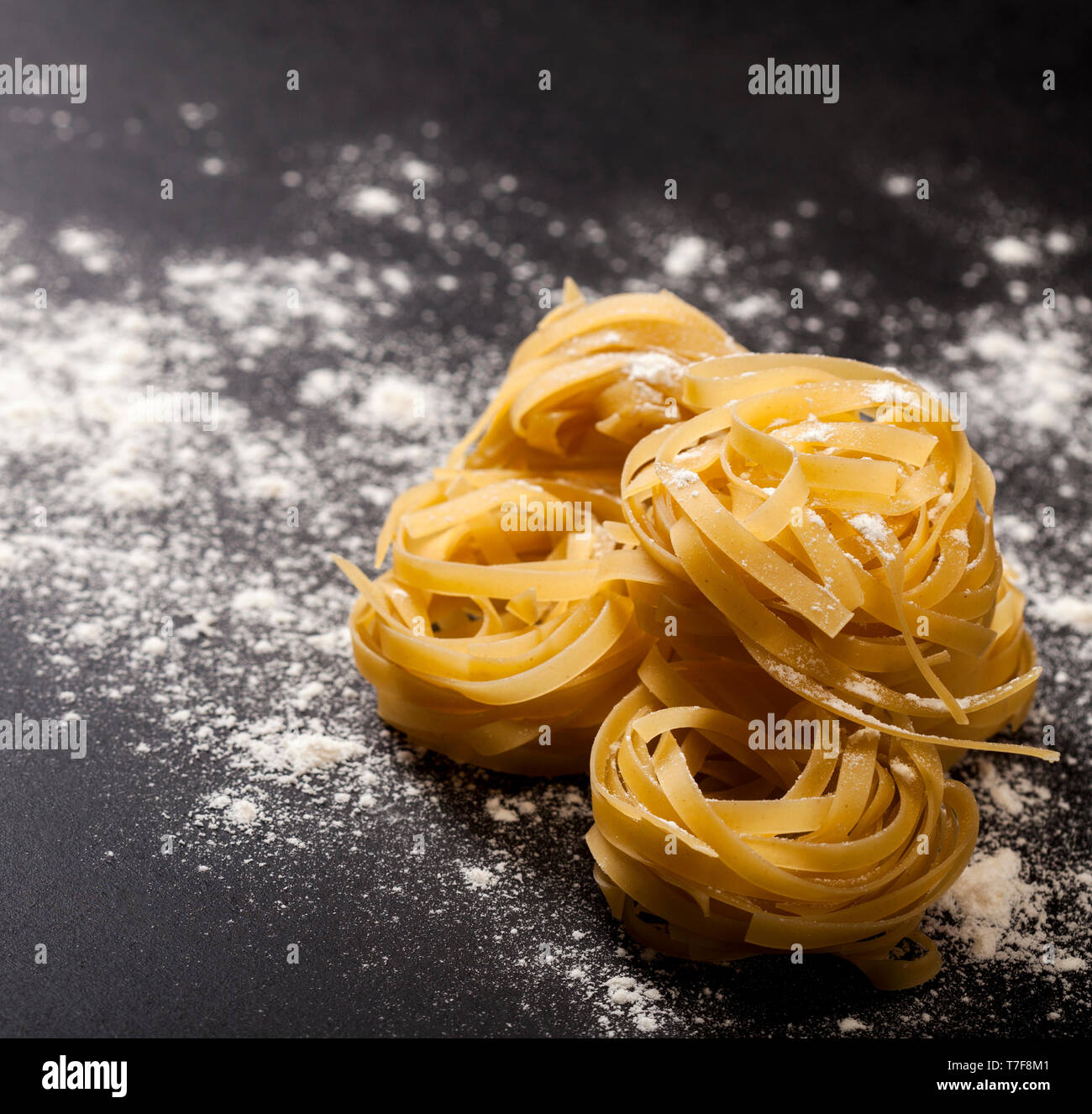 Italian traditional raw pasta on the black stone background. Closeup ...