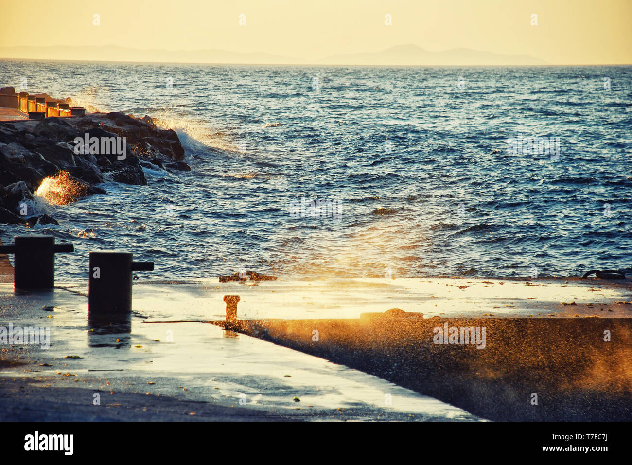 Seashore dock at sunset with waves Stock Photo - Alamy